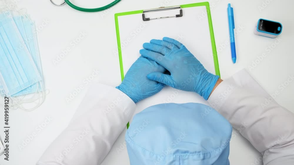 op view of the doctor's desk, who is bent over in a prayer position ...