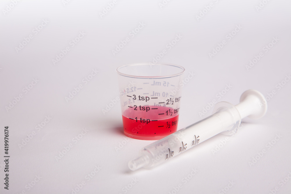 Syringe and medicine measuring cup Stock-Foto | Adobe Stock