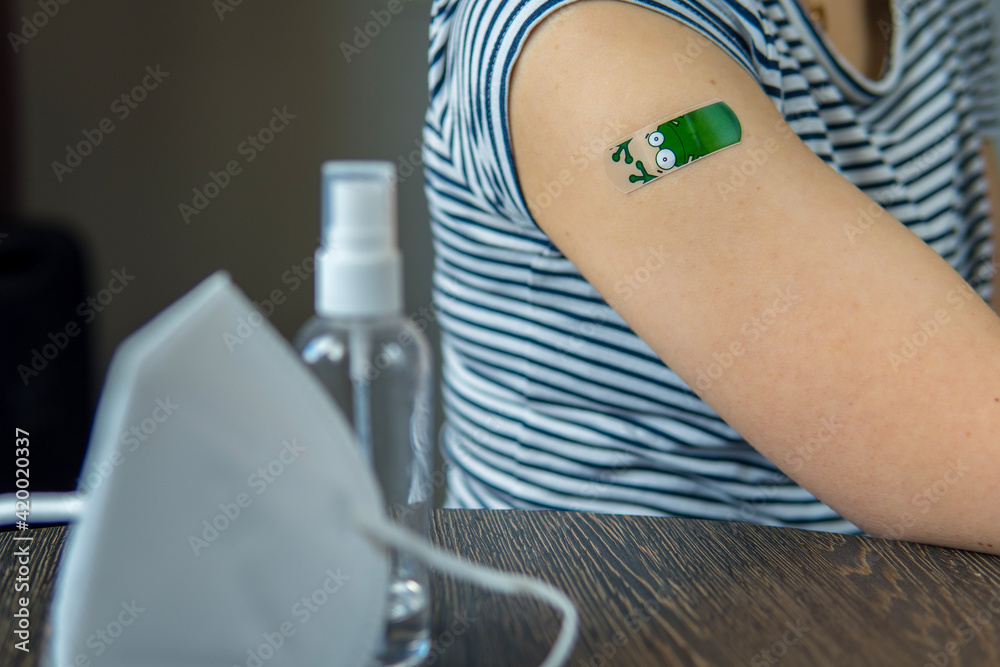 Arm of a woman with a colorful adhesive bandage after injection of ...