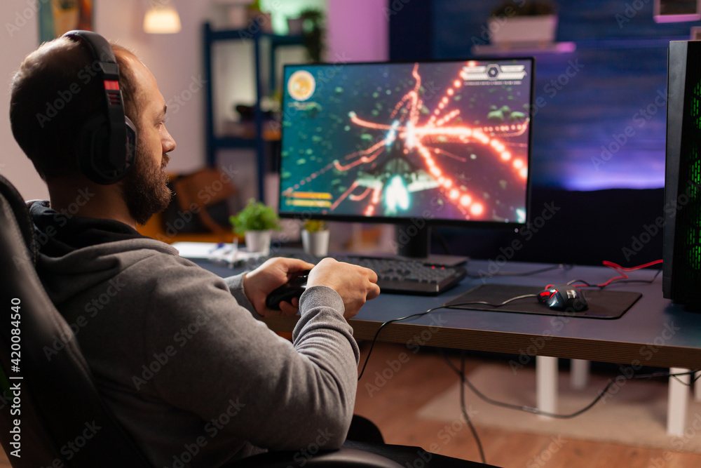Concentrated gamer playing virtual game on powerful computer at home ...