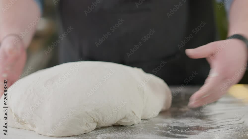 Male hands kneading raw dough on metal kitchen table covered with flour ...
