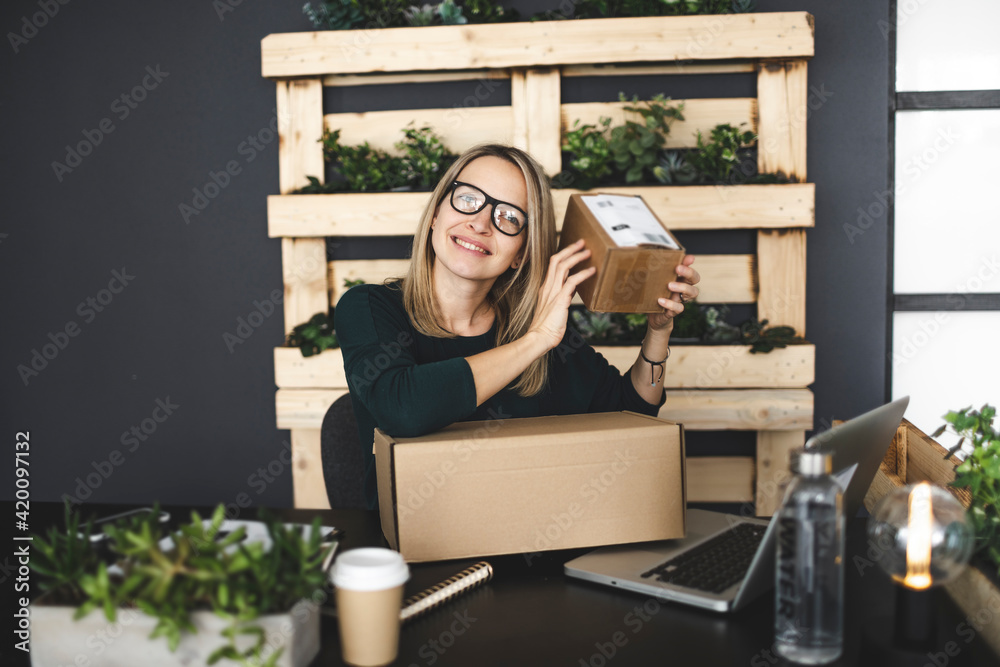 pretty young blonde woman with brown parcels is sitting in front of ...
