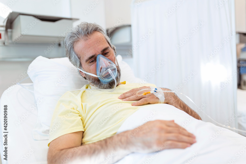 Portrait of retired senior man breathing slowly with oxygen mask during coronavirus covid-19 ...