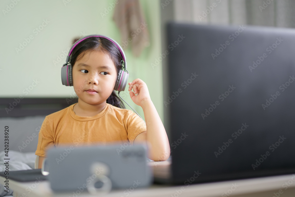 Asian child or kid girl smile e-learning on computer notebook and smartphone to wearing ...