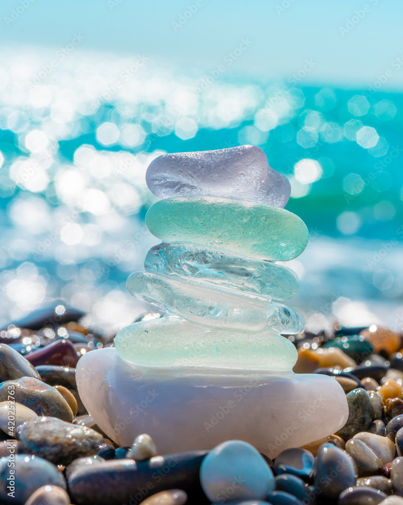 Sea glass stones arranged in a balance pyramid on the beach. Beautiful ...
