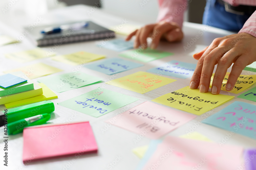 Business woman working on a project using sticky notes on her desktop ...