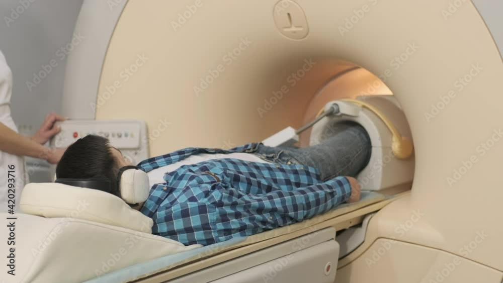 Woman doctor makes knee-joint MRI scanning. Young man patient on ...