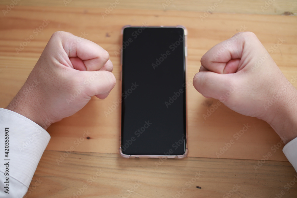 Angry man clasp his fist on table with smart phone, mobile phone mock ...