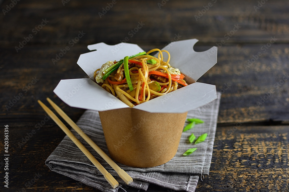 Traditional Chinese wok noodles with vegetables and meat, in a box with ...