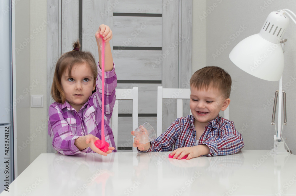 Little kids playing with pink slime at home. A fashionable liquid toy ...