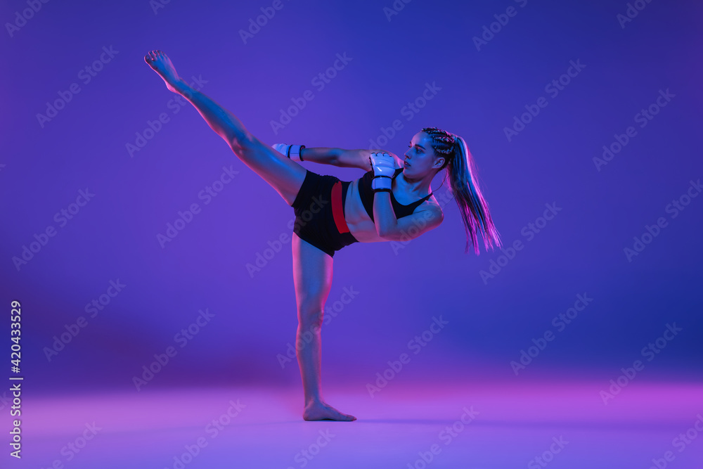 Young female MMA fighter posing isolated over blue-pink background in ...