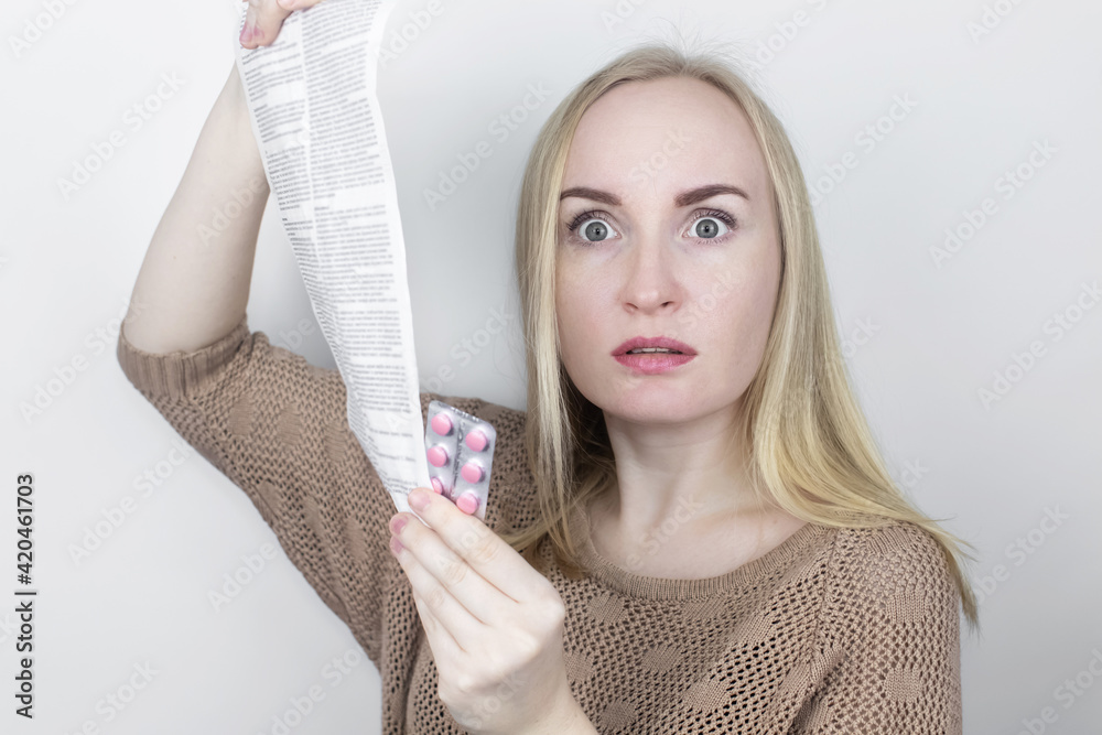 Girl on a white background reads the instructions for medicines. The ...