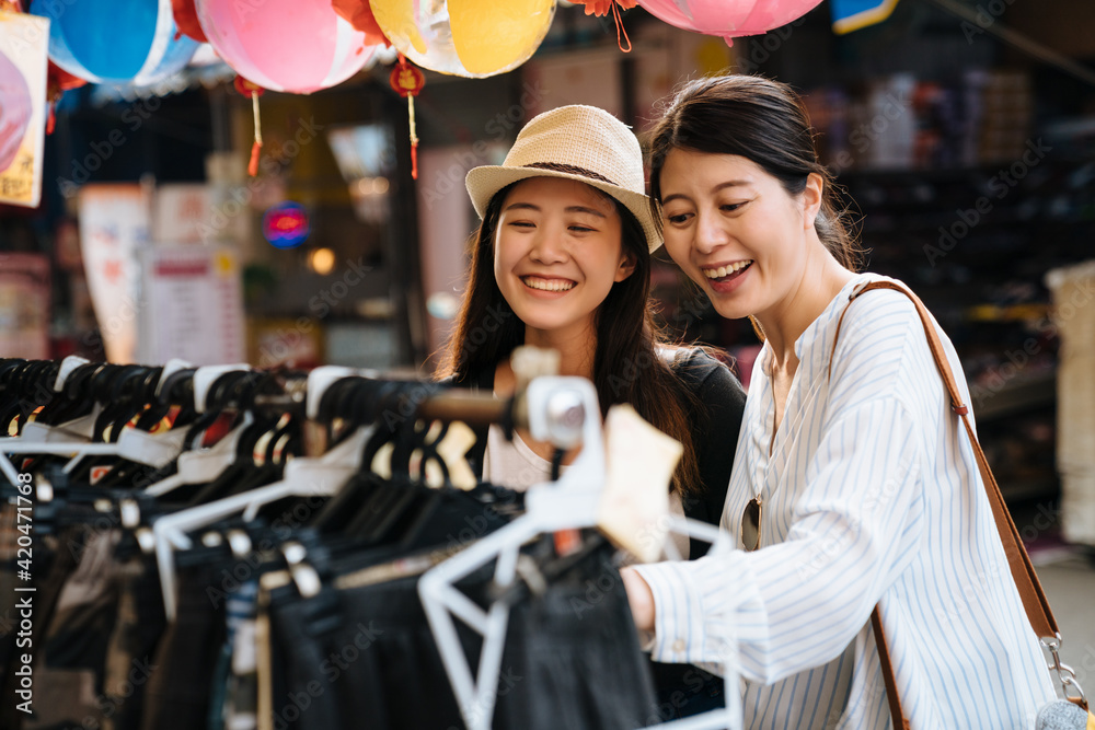 two asian japanese young women friends buying clothes in local market ...