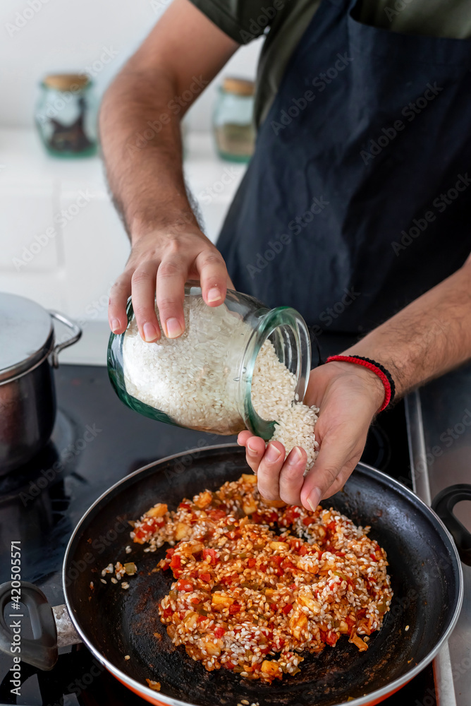 Cook throwing rice into the pan to prepare a spanish paella Stock Photo ...