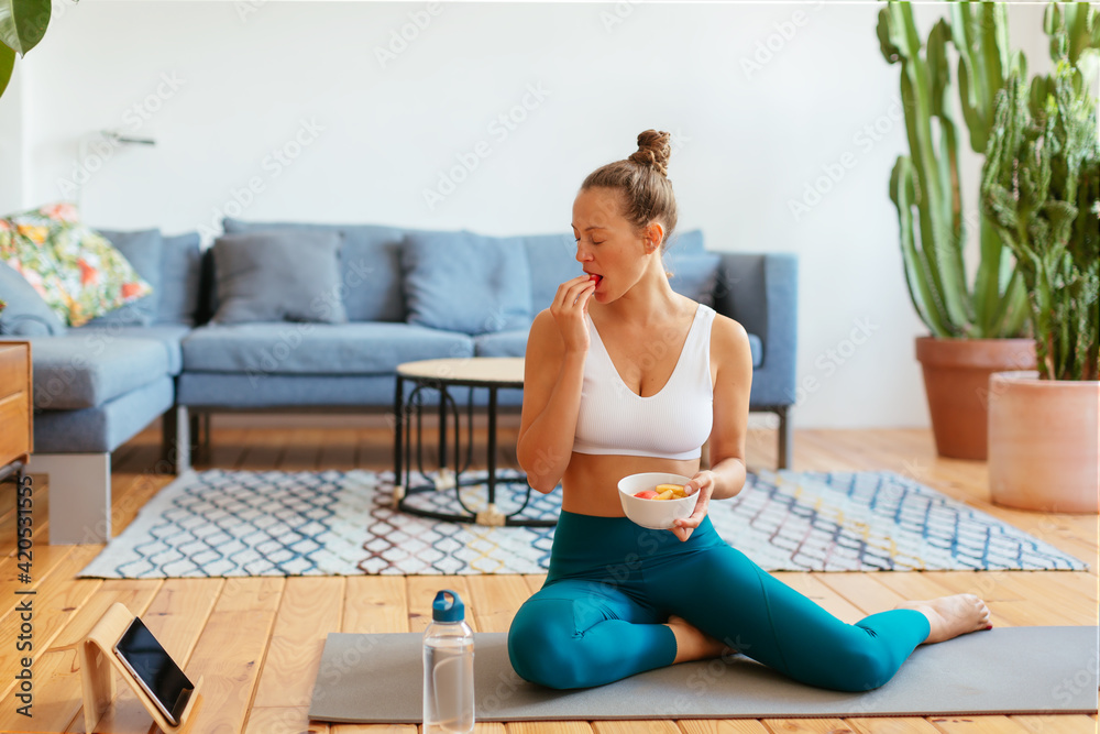 Female athlete eating healthy food and watching video Stock Photo ...