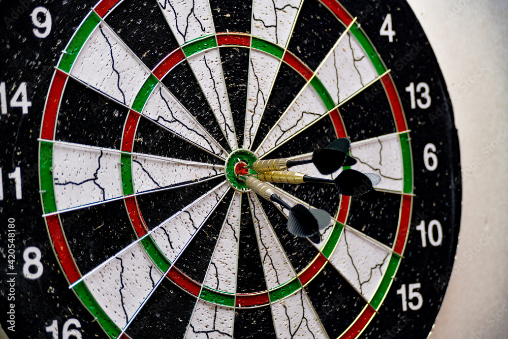 Three darts hit the center of the board while playing darts. Stock ...