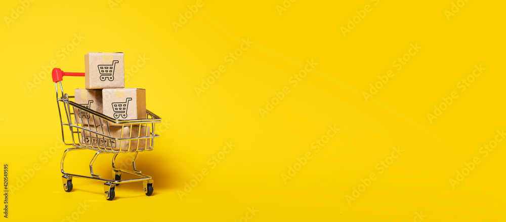paper boxes parcel in a trolley isolated on yellow background. shopping ...
