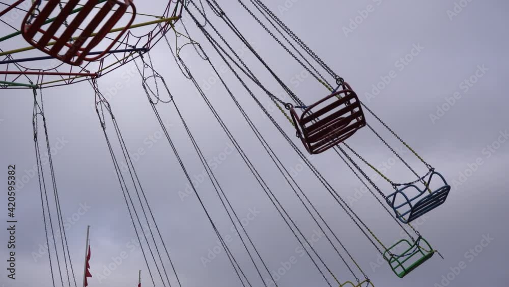 Two children ride a circular carousel on chains against the background ...