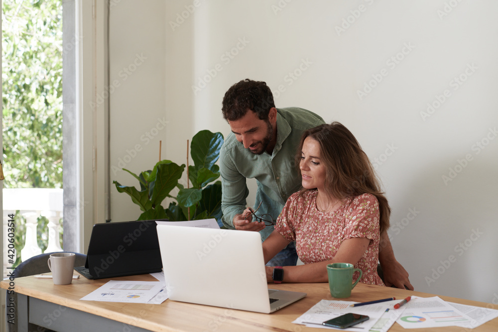 Man helping his female colleague at work. Stock Photo | Adobe Stock