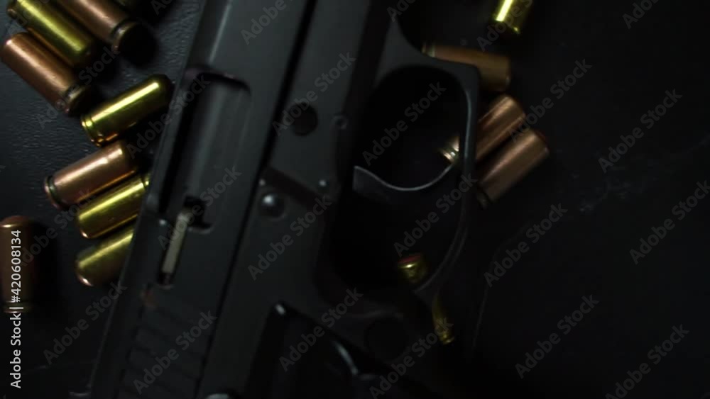 Firearms and ammunition lie on a black textured table. Copper bullets ...