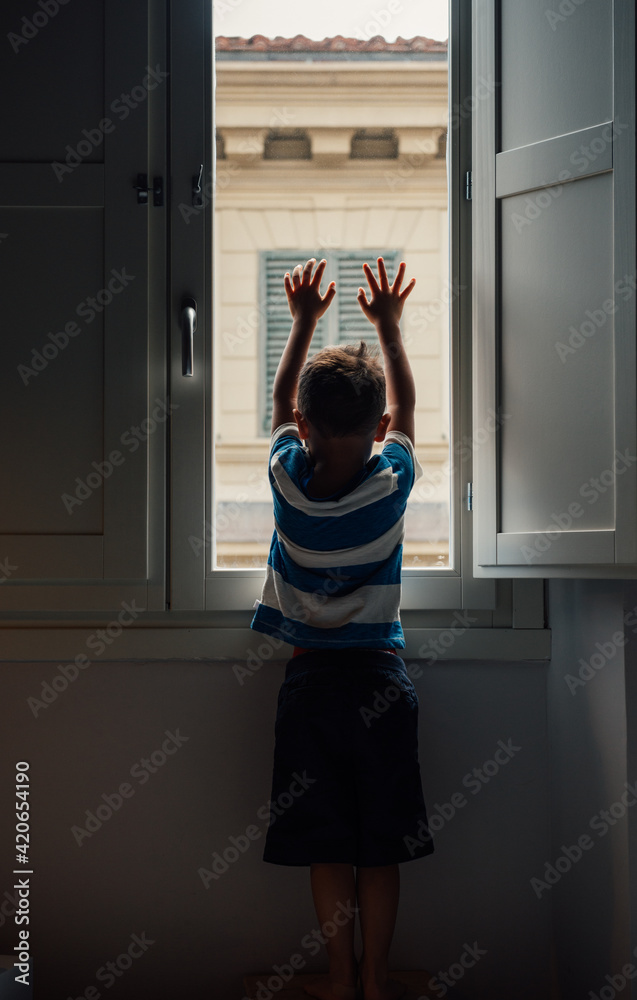 Little boy stuck indoors and looking out his second floor window. Stock ...