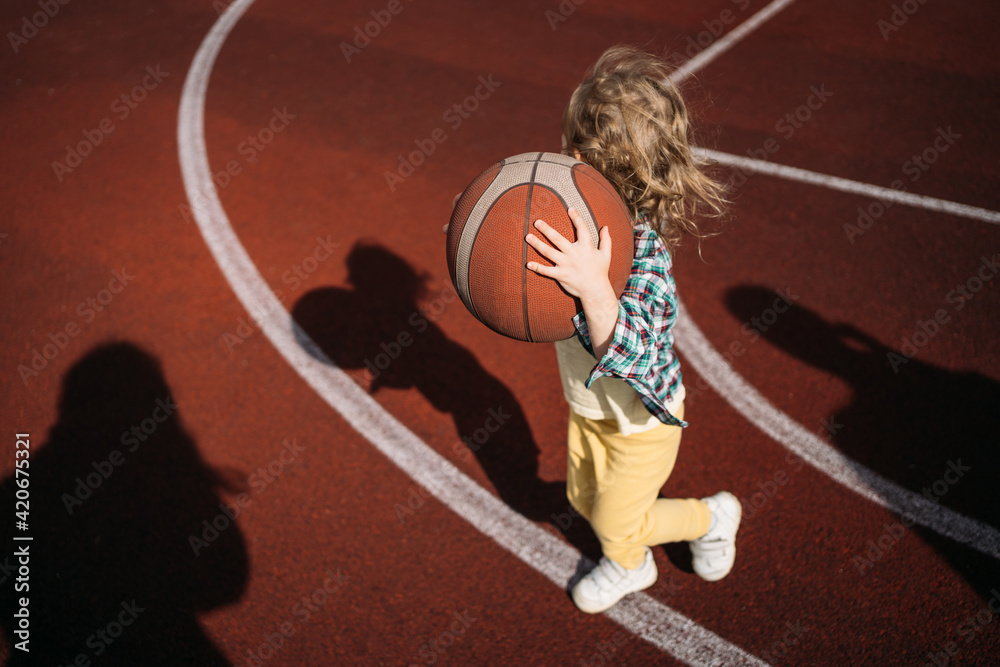 Little kid playing basketball ball on sports ground Stock Photo | Adobe ...