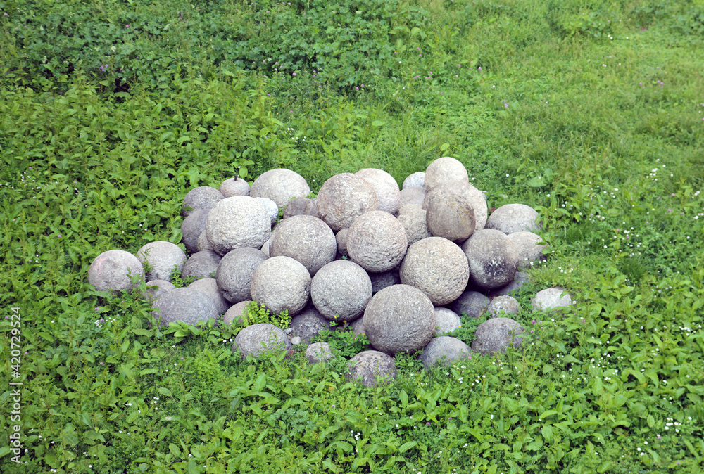 pile of ancient medieval round stone granite cannonballs lie in the ...
