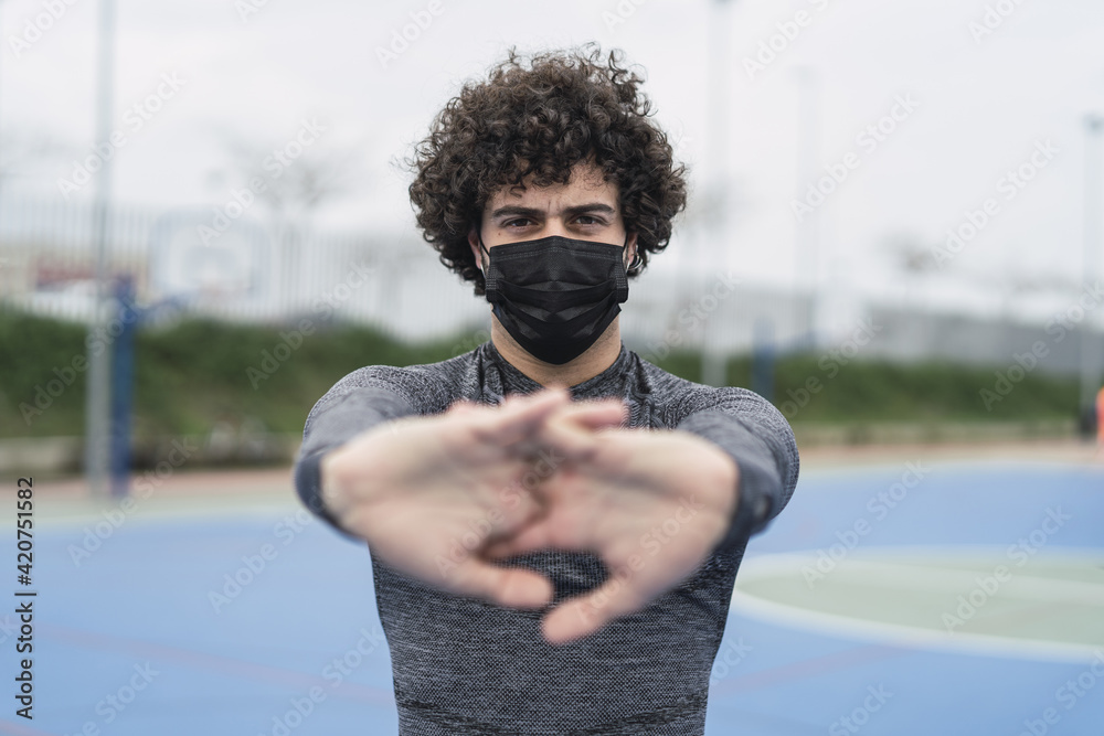 Young athletic male wearing a black mask has interlaced the fingers and ...