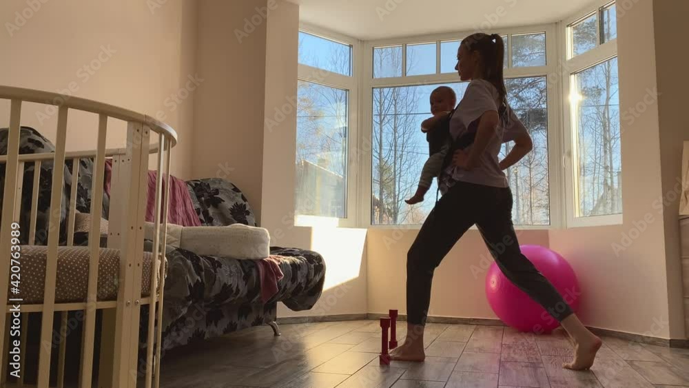 A young mother performs sports exercises squats and lunges with the ...