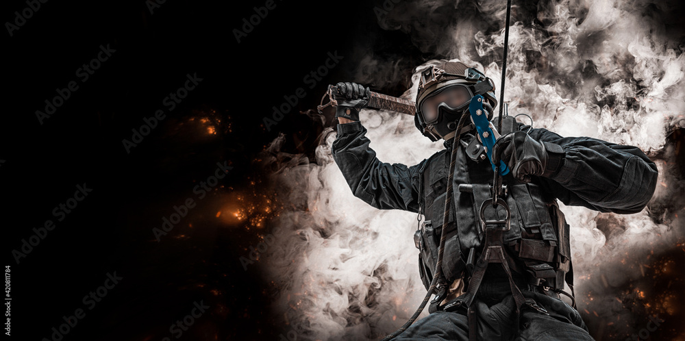 Special forces soldier hangs on a rope and swings with a special device ...