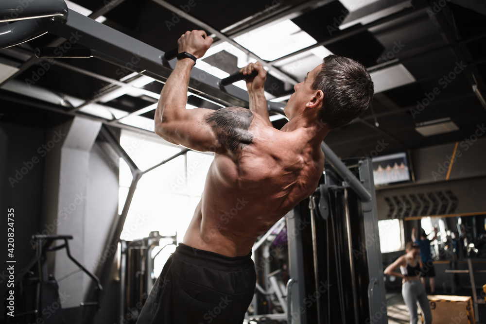 Shirtless ripped male bodybuilder doing pull ups at the gym Stock Photo ...