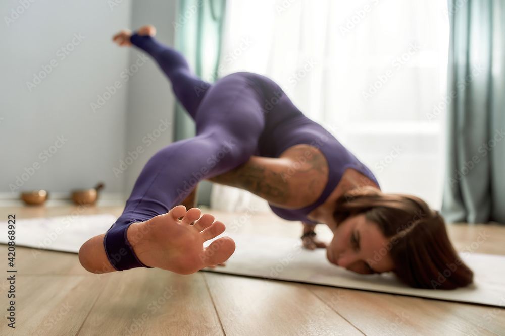 Athletic woman in tight sportswear practicing yoga, doing Side Crow ...