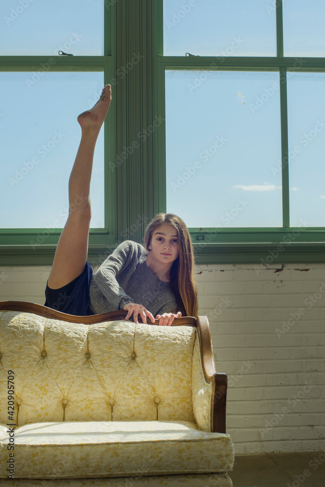 Teenage girl in dance studio behind sofa with leg raised, portrait ...