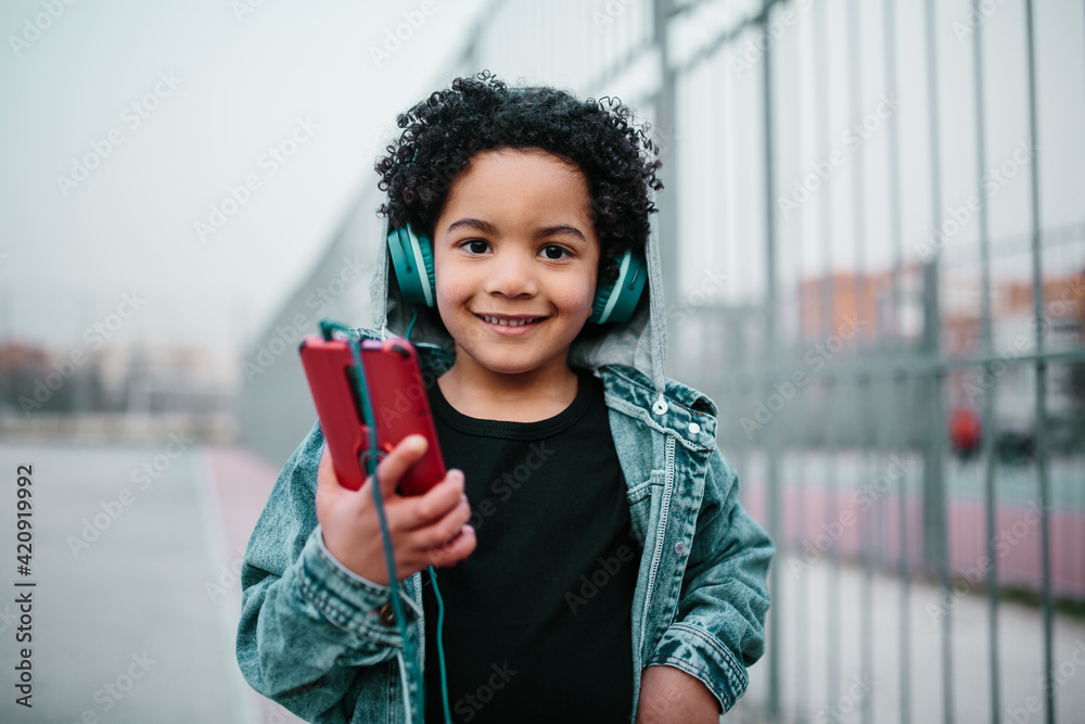 Afro child with smart phone and headphones, smiling, with expression of ...