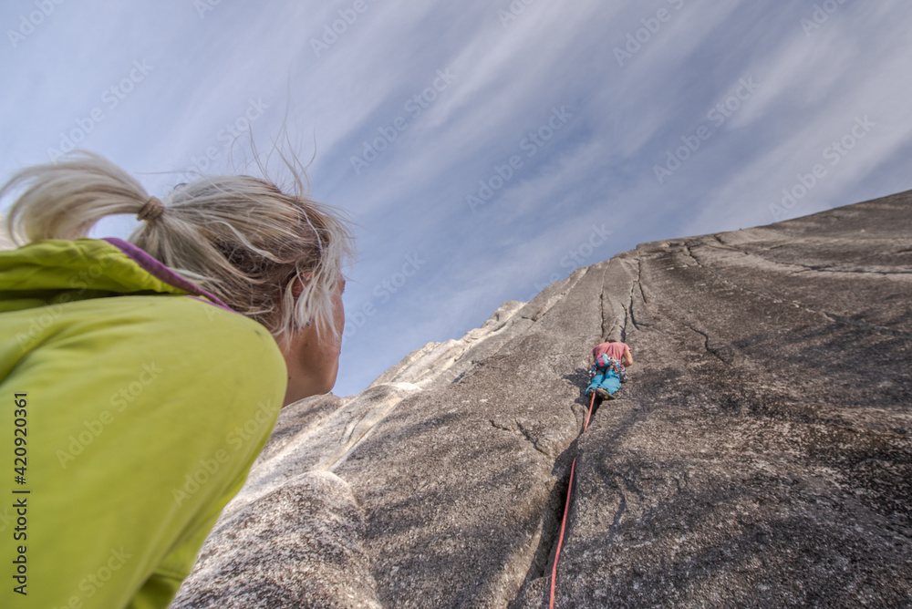 Rock climber watching friend climb the sheer cliff, Heatwave, The Chief ...