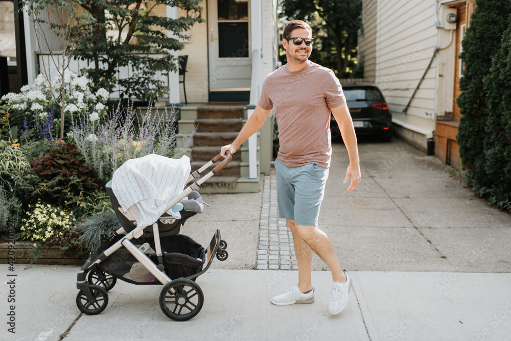 Father pushing baby carriage on pavement Stock Photo | Adobe Stock