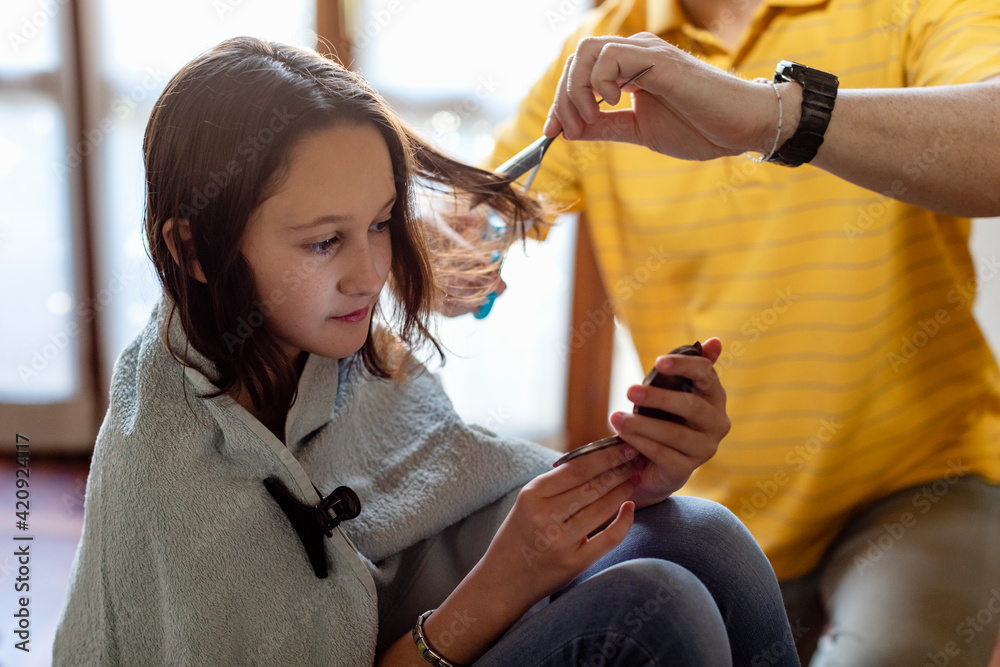 Father cutting his daughter's hair at home, during the stay at home ...