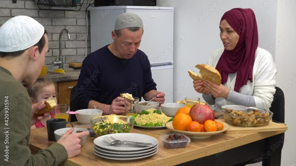 Fasting Muslim family sits together at the table during Ramadan at home ...