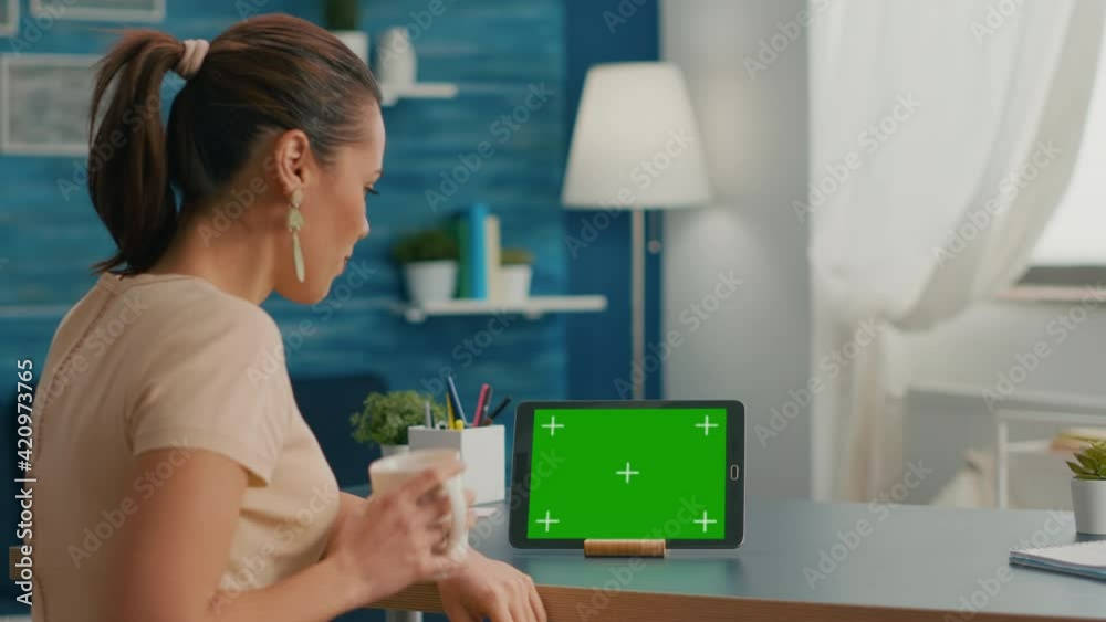 Caucasian female looking at tablet computer with mock up green screen ...