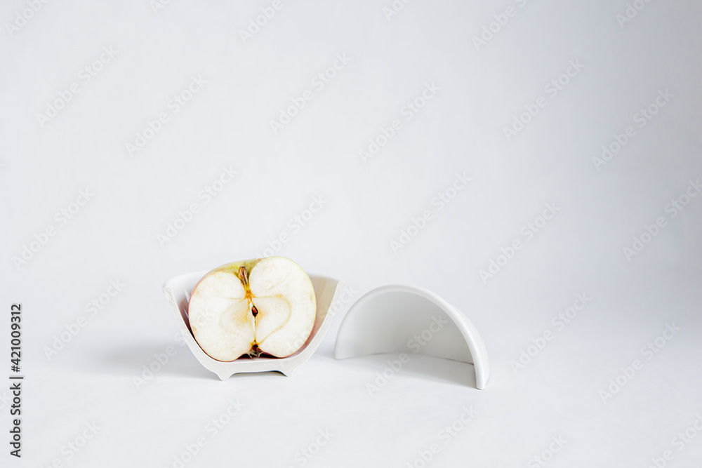 Sliced half of an apple in a broken half of a ceramic small platter on ...