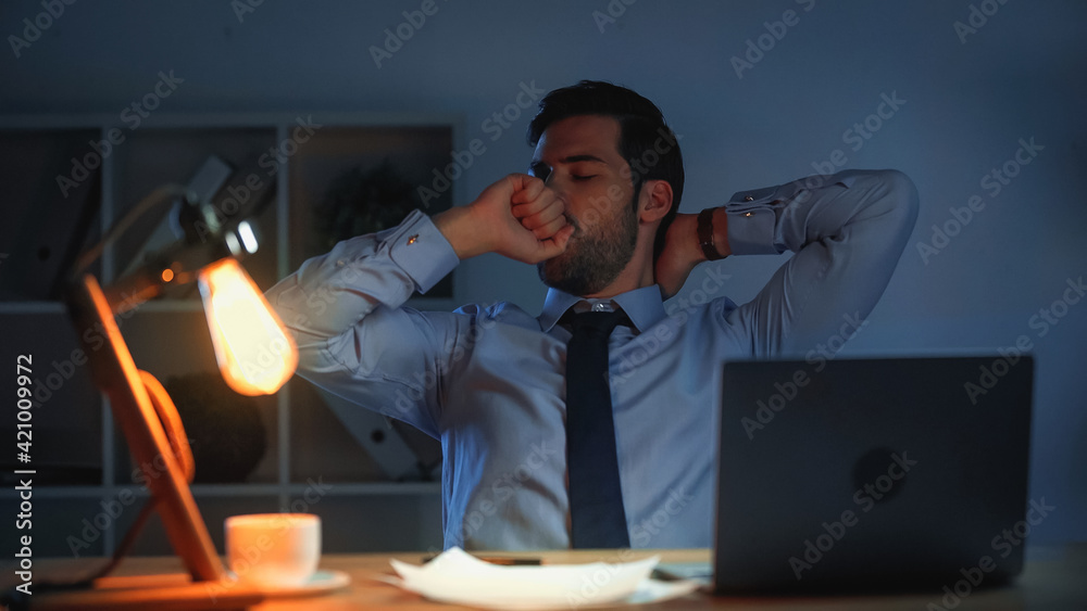 tired businessman yawning while working late in office Stock Photo ...