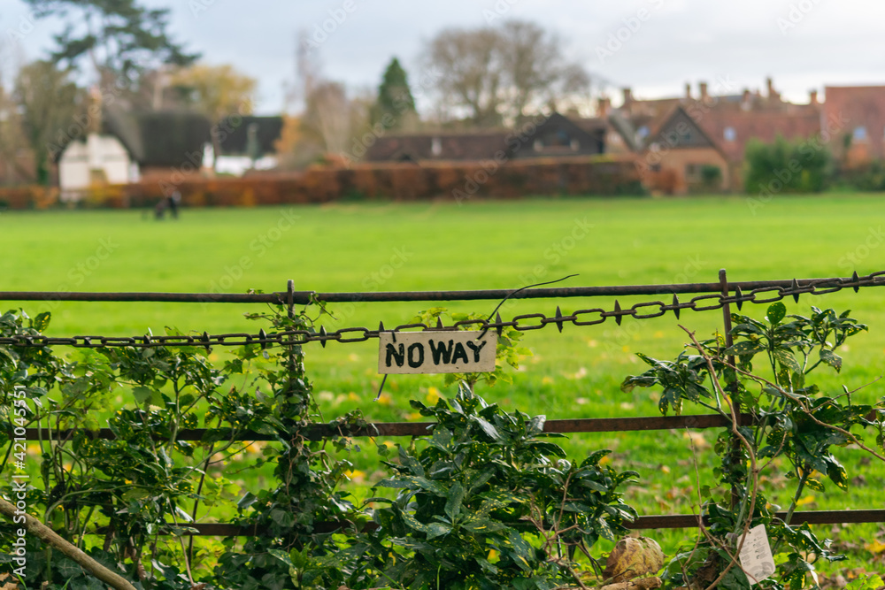 No way sign hanged on a metal fence with beautiful big green park and ...