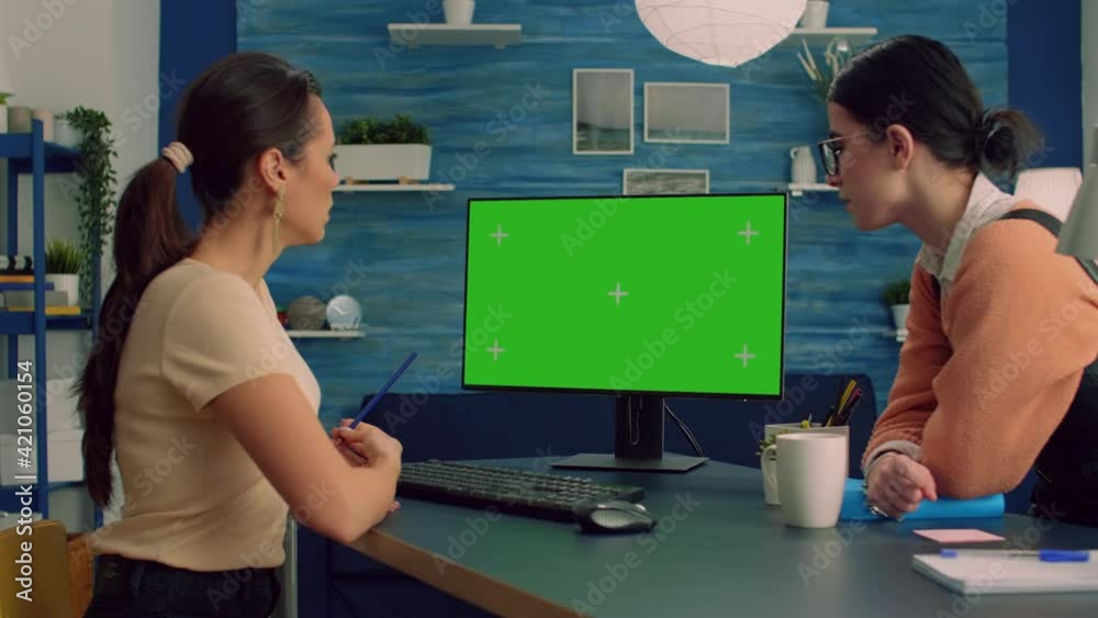 Two collegues working together on computer with mock up green screen ...
