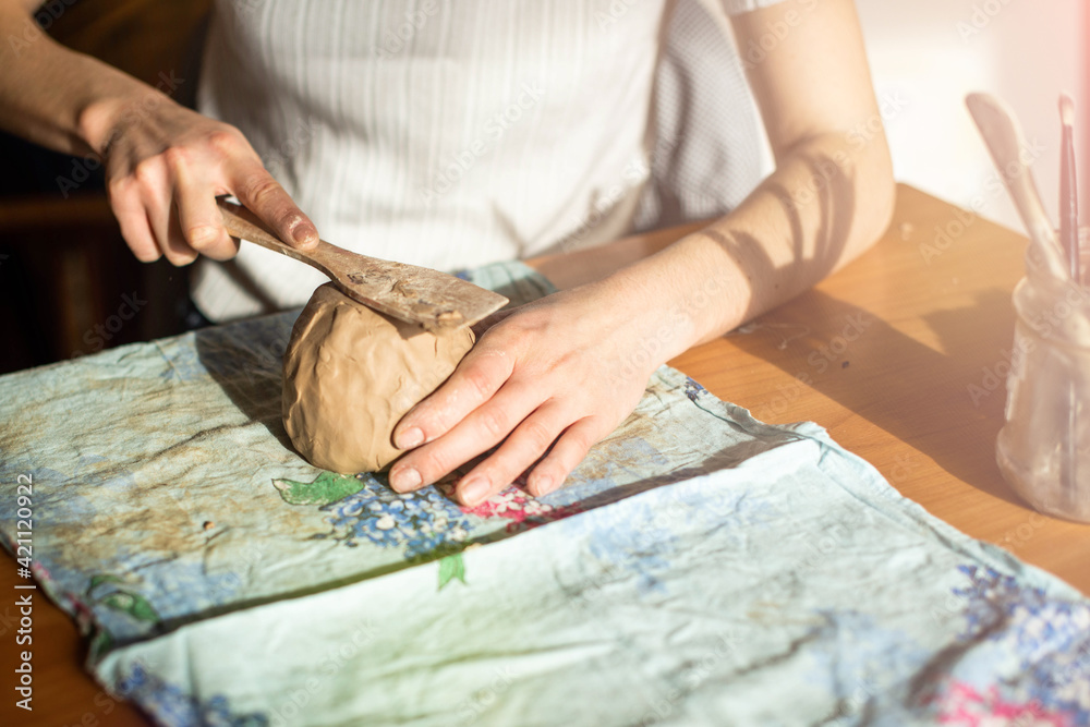 Pottery. A girl with a string in her hands cuts the top layer off clod ...
