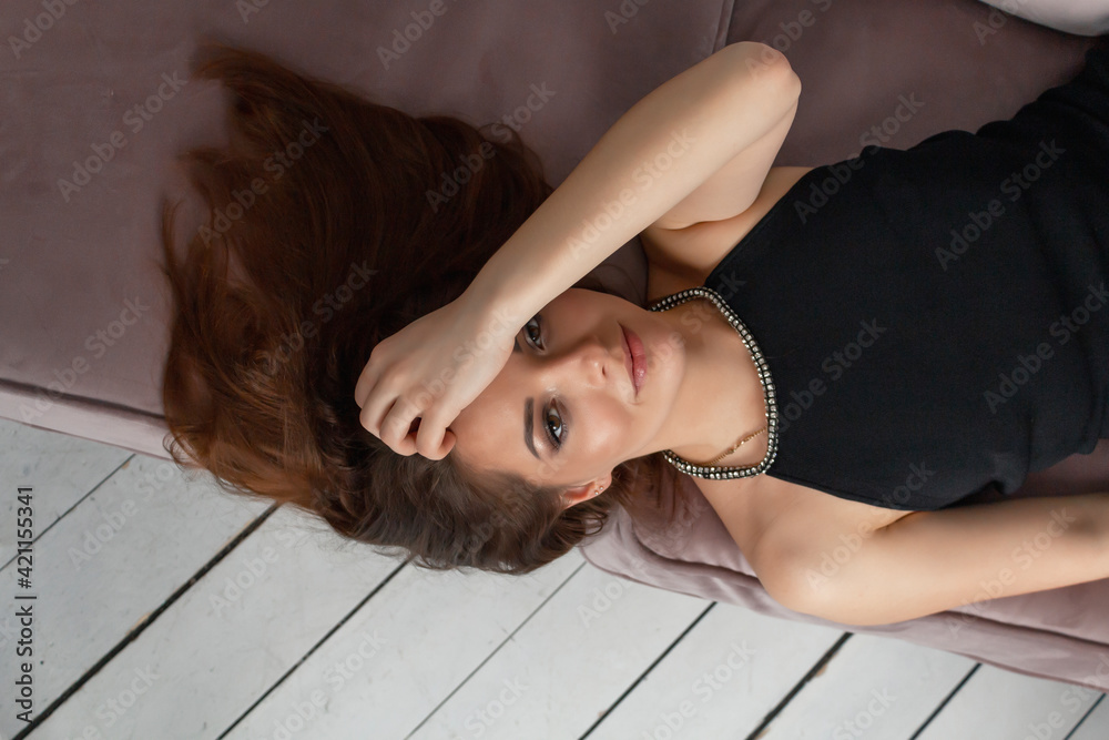 A happy, beautiful, successful woman with long hair lay down on a sofa ...