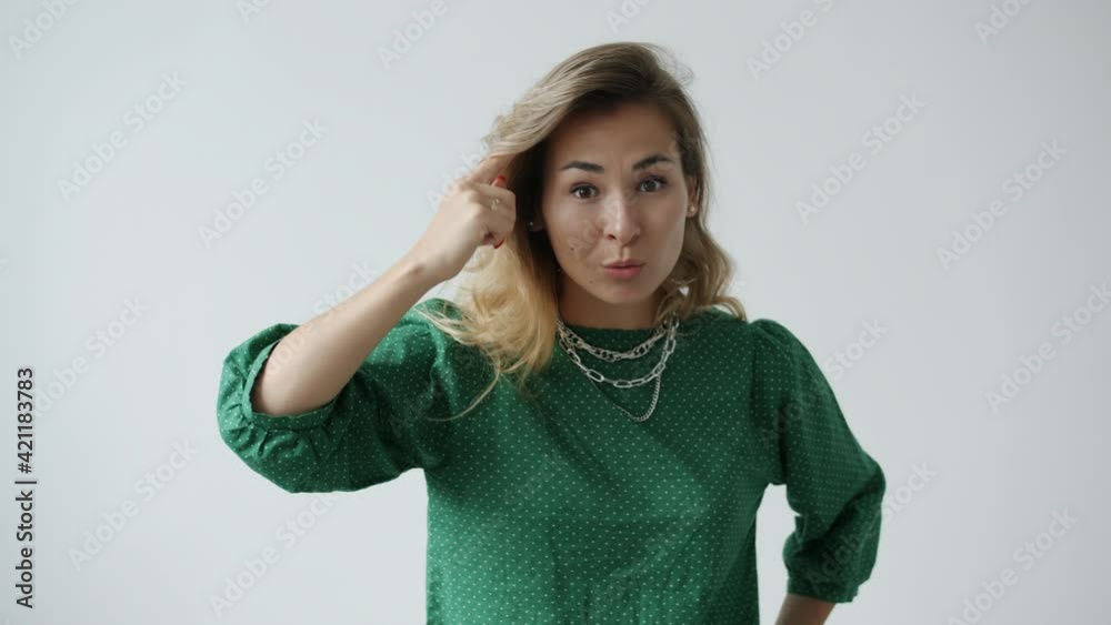 Portrait of emotional young woman showing fool hand gesture twisting ...