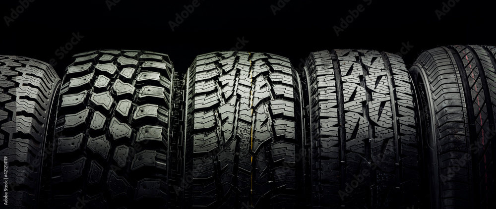 off-road tires and tires for crossovers and SUVs stand in a row on a ...