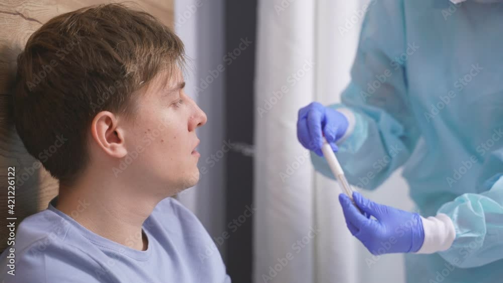 Health professional in PPE suit introducing a nasal and throat swab to ...