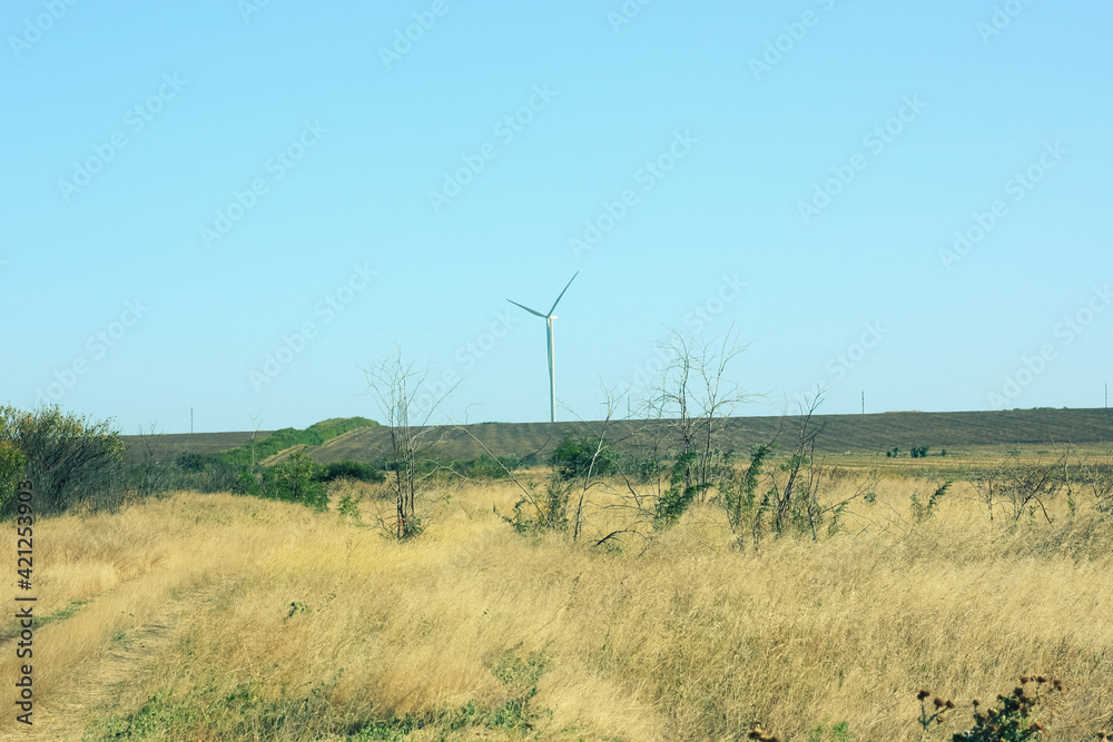 Wind turbines energy converters on wild grass field on sunny day. Local ...