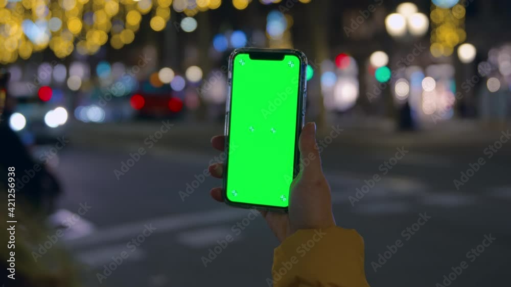 Woman hold smartphone with green screen. Background of busy bustling ...